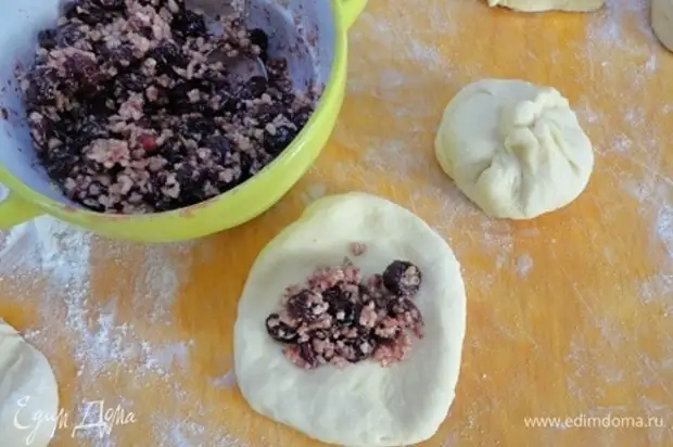 Massa dividida em 16 partes iguais. De cada pedaço de mãos para formar um bolo, coloque 1 colher de chá no meio. Recheio, leve as bordas para o centro.